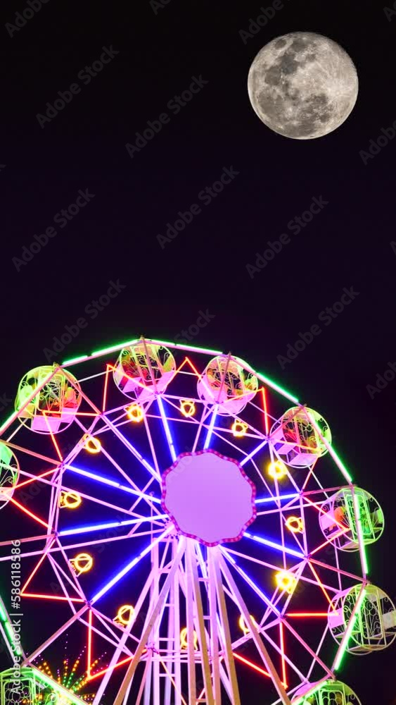 vertical footage of a ferris wheel decorated with colorful lights ...