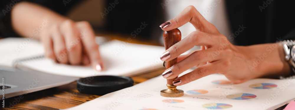 Person's hand stamping with approved stamp on certificate document ...