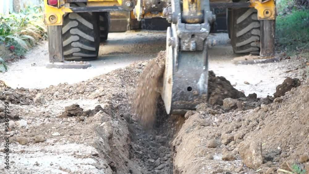 Excavator digs a trench to lay pipes. Close up of an excavator digging ...