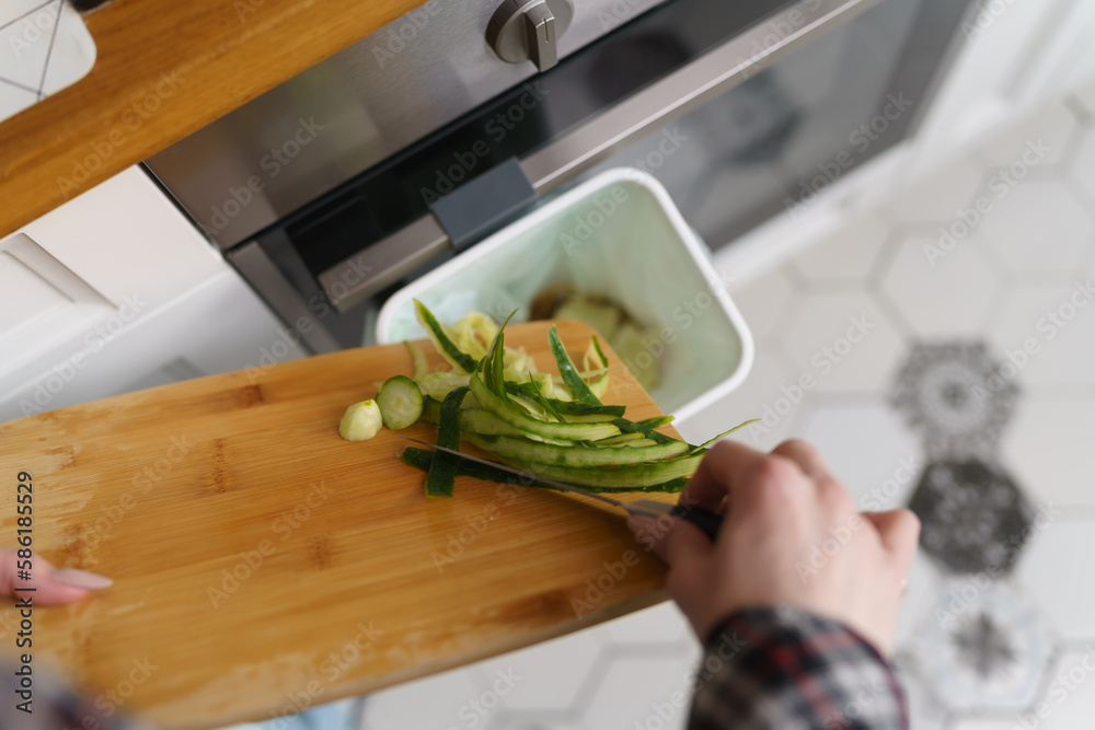 Cook throwing cucumber peels in a bokashi container for decomposition ...