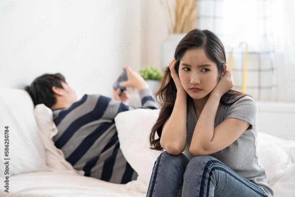 Asian young upset woman sitting on the bed, against her boyfriend, Wife ...