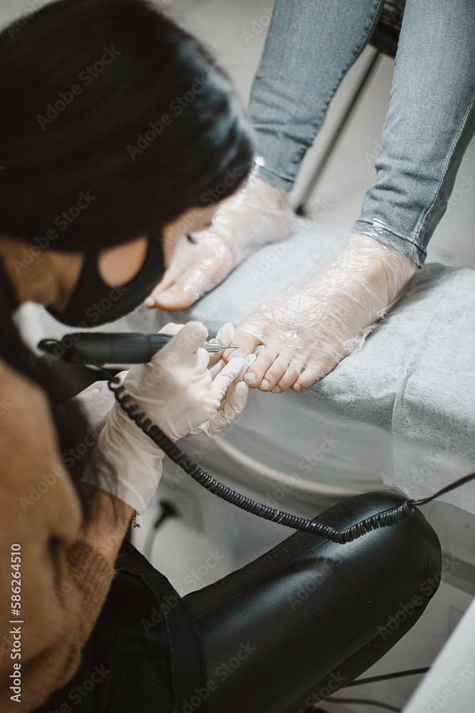 A pedicure master cleans and paints the toenails of a young girl who ...