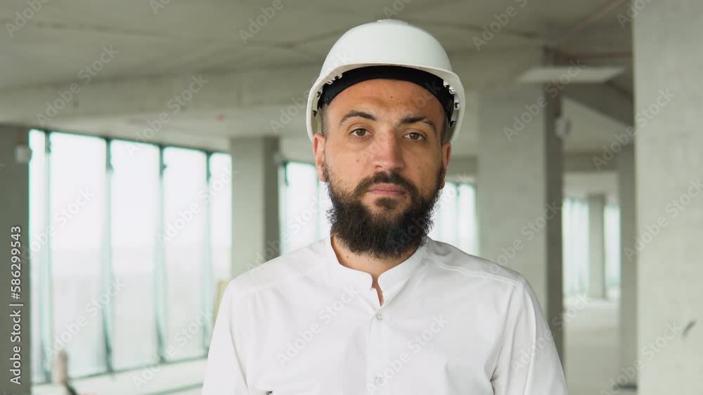 Confident Arabian Middle Eastern civil engineer wearing a safety helmet ...