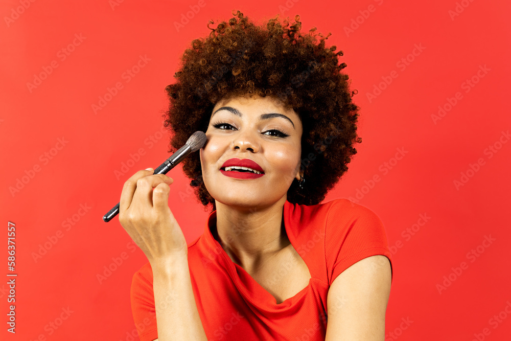 Portrait of a dark-skinned girl with afro hair posing on a red ...