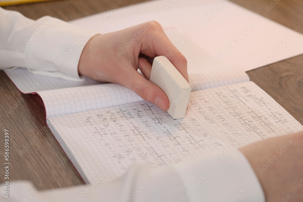 Girl erasing mistake in her notebook at wooden desk, closeup Stock ...