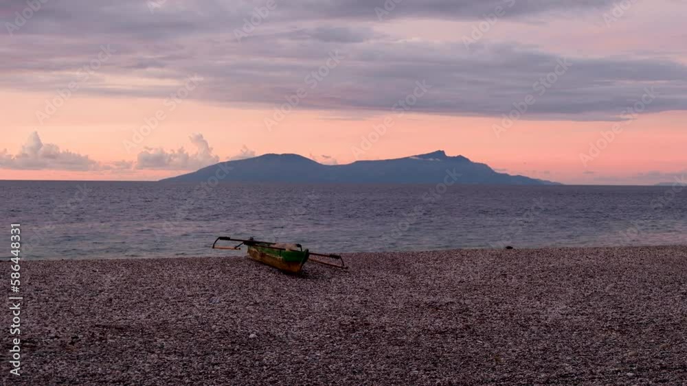 Timorese wooden fishing boat canoe resting on the beach with tropical ...