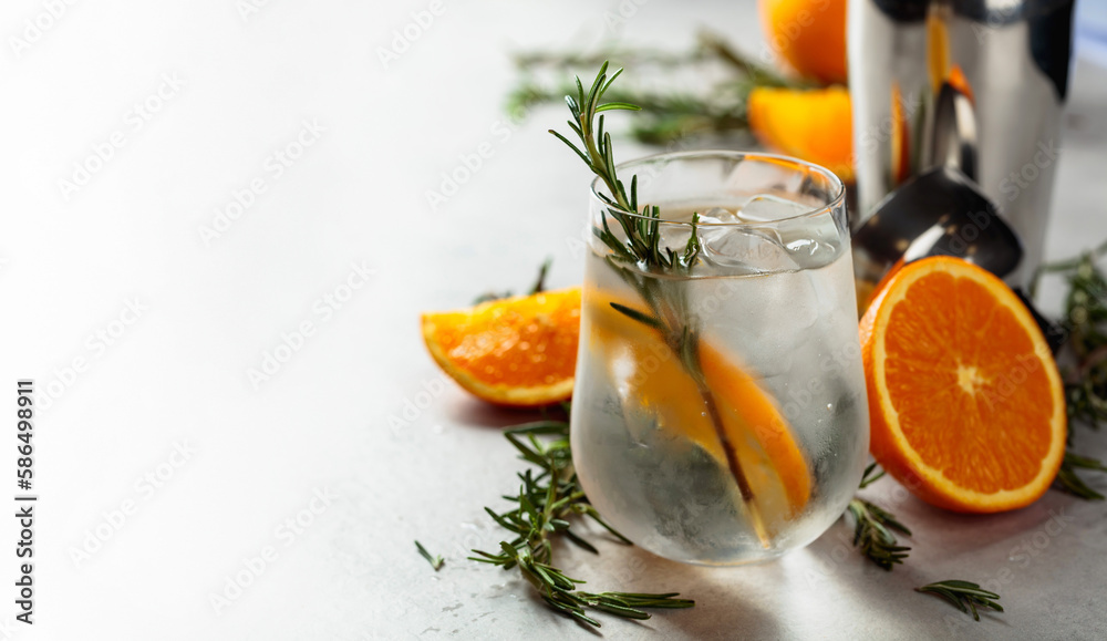 Gin and tonic cocktail with natural ice, orange, and rosemary in a ...