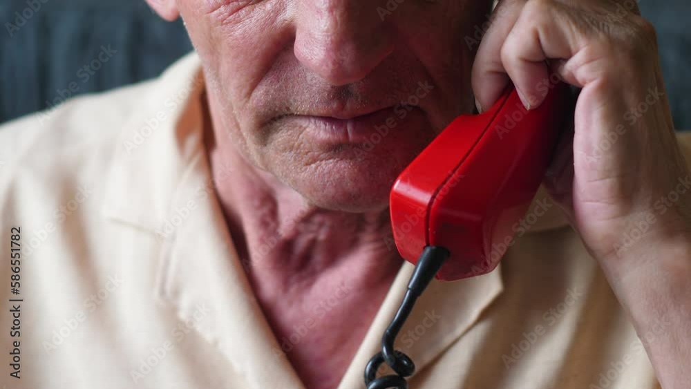portrait of a serious elderly man holding a telephone receiver and ...