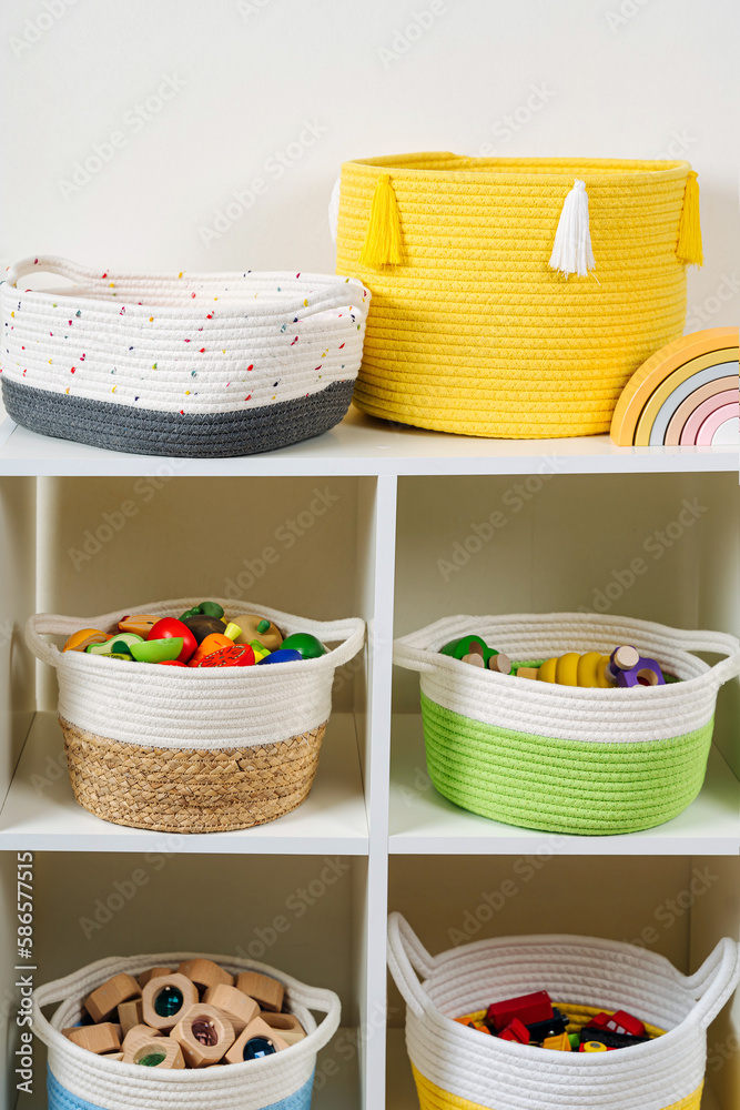 Colorful storage baskets on shelves. White shelving with rainbow wooden ...