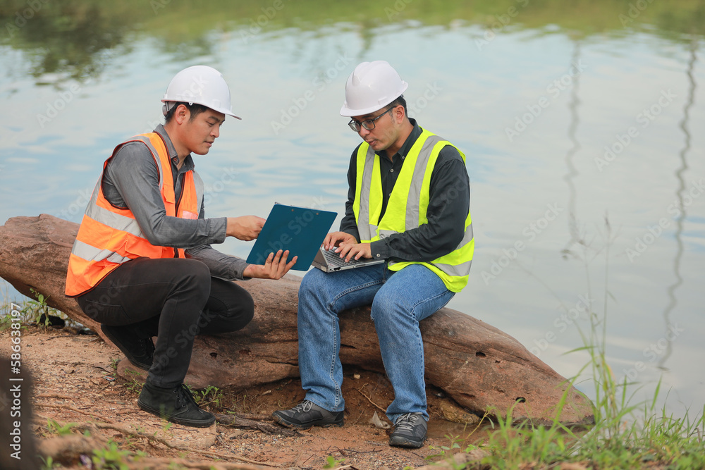 Environmental two engineers work at water source to check for contaminants in water sources and ...