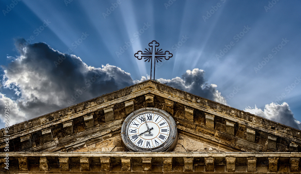 crucifix on a church roof with clock and radial sky light Stock Photo ...