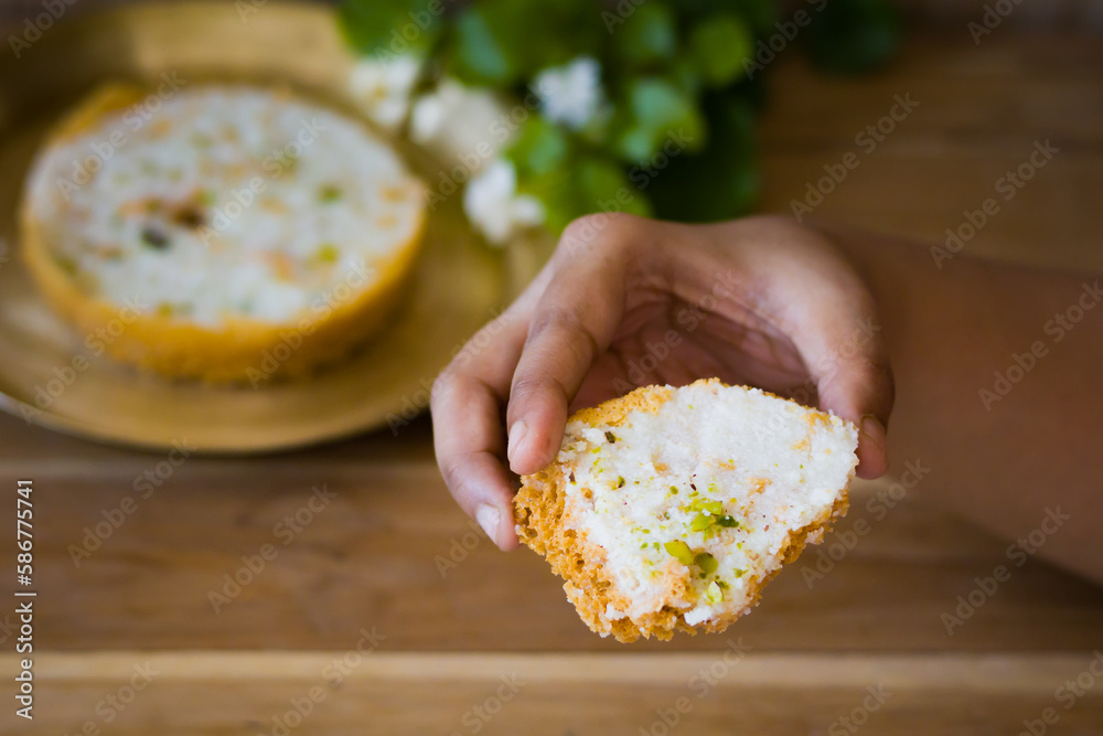 hand holding a piece of Ghewar or ghevar, which is a traditional sweet ...