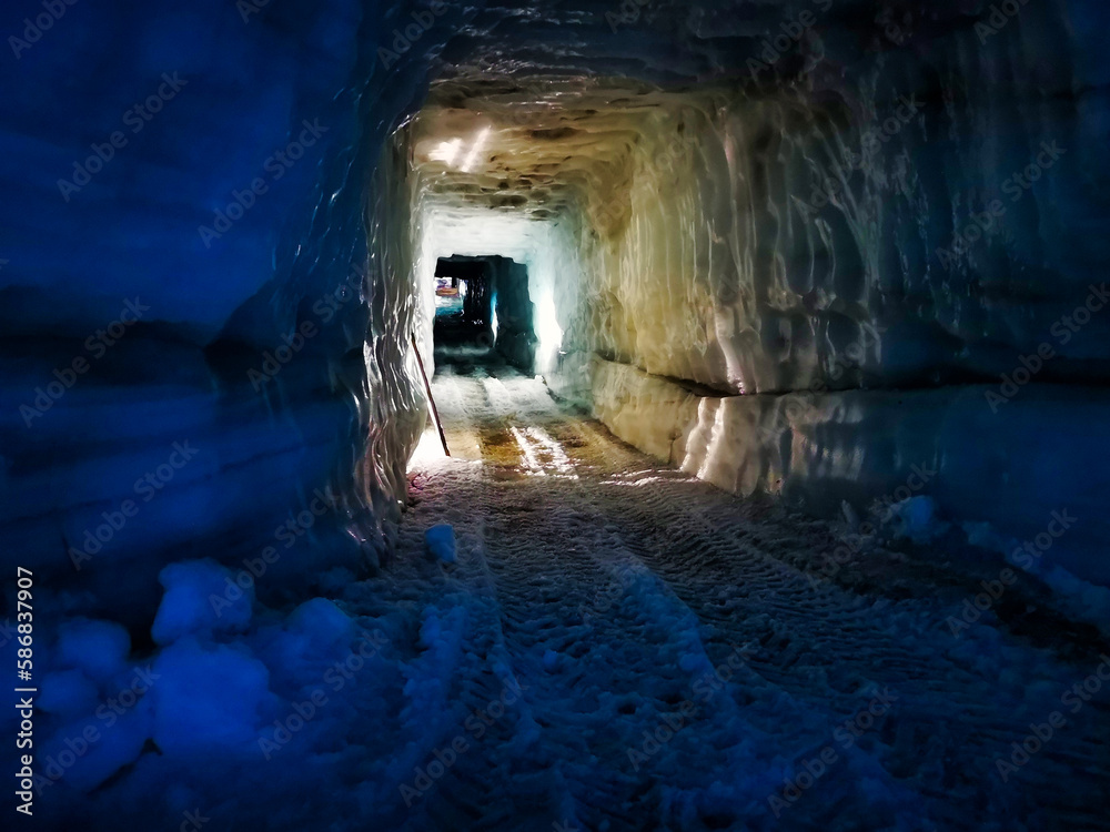A man-made ice tunnel in Iceland, illuminated with soft lights, reveals ...