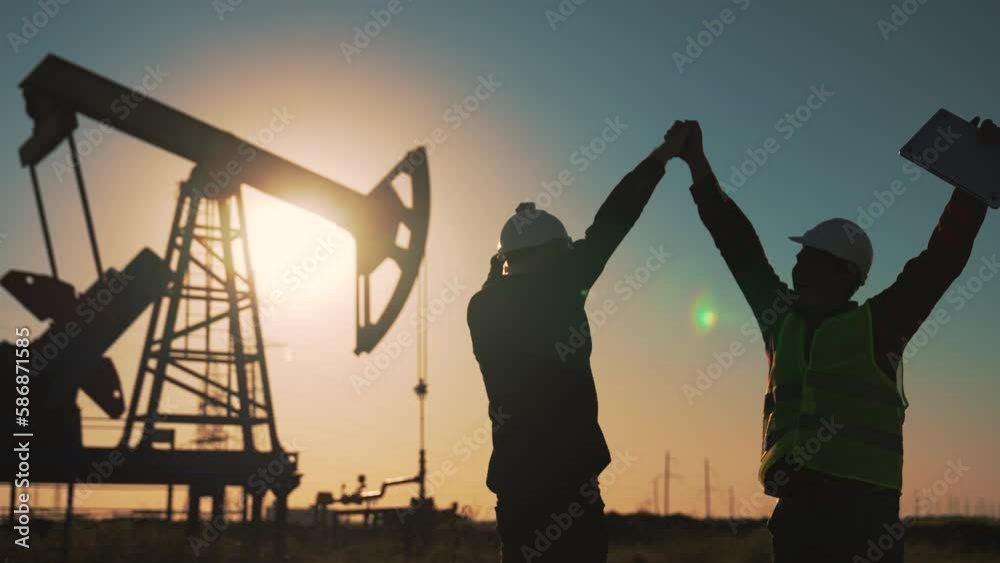 Teamwork.Oil engineer in helmet work with an oil pump.Silhouette of ...