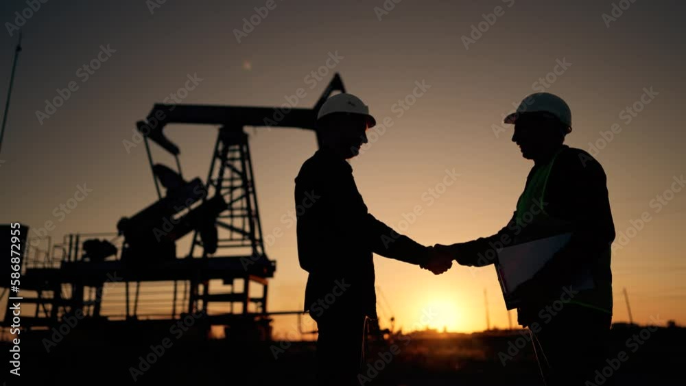 Oil pump. Engineers handshake. Corporate contract. People in helmets ...