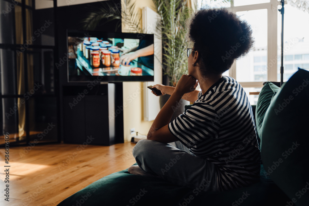Back view of afro woman watching tv while sitting on couch Stock Photo ...
