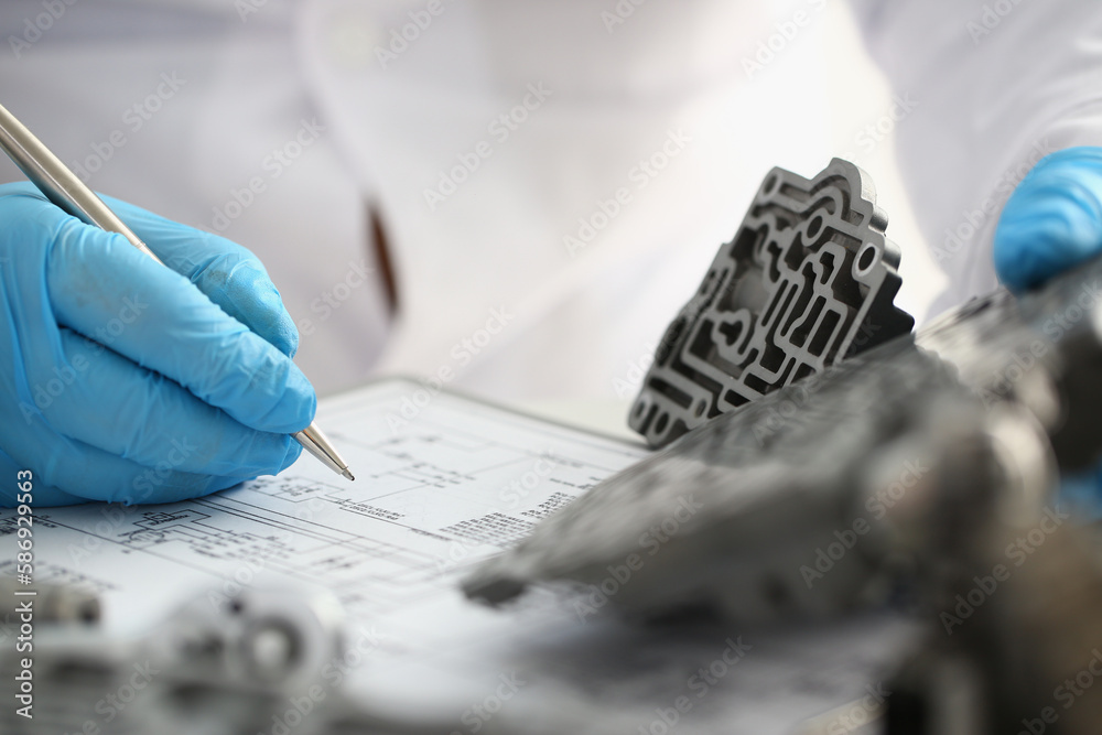 Scientist mechanic in gloves conducts technical research of car gearbox ...