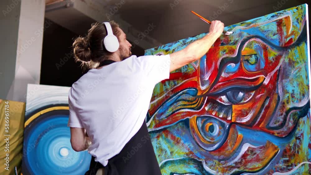A skilled imaginative artist wearing white headphones, painting with ...
