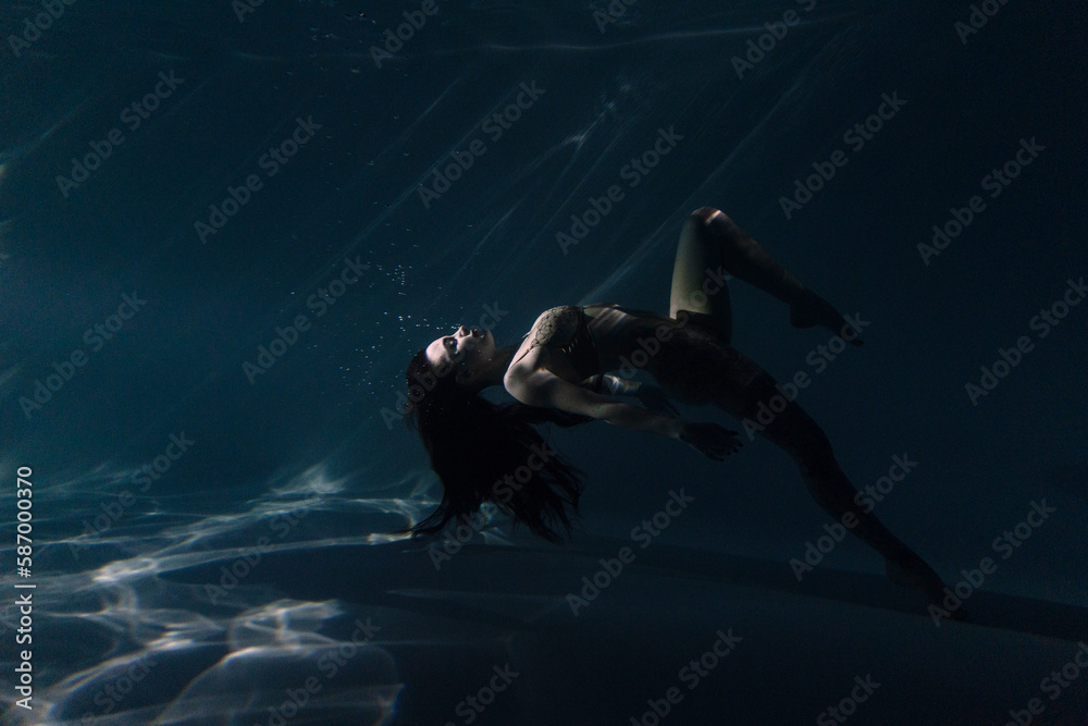 Underwater shoot of beautiful woman with long hair dancing in water in ...