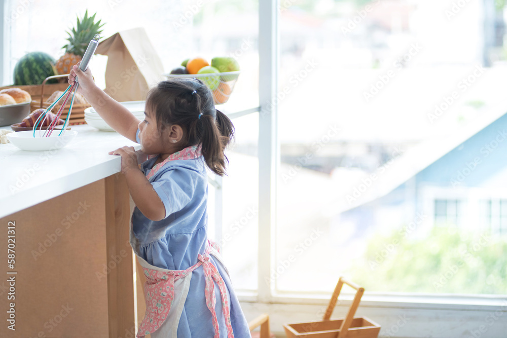 Cute little girl enjoys cooking in the kitchen, pretend to be a chef ...
