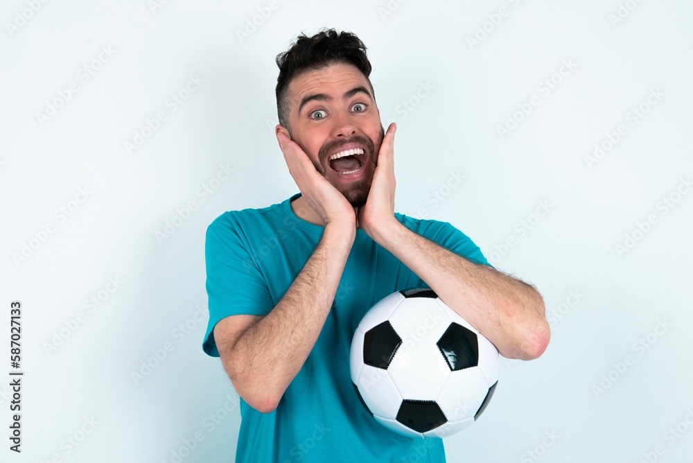Happy Young man holding a ball over white background touches both ...