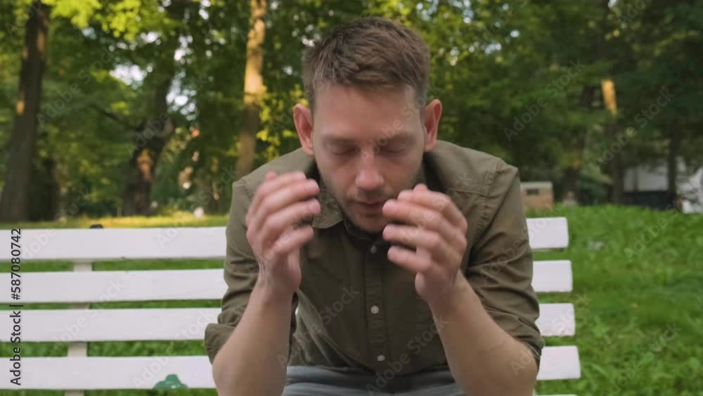 Sad man sitting outdoor on the bench in the park. Depression, crisis ...
