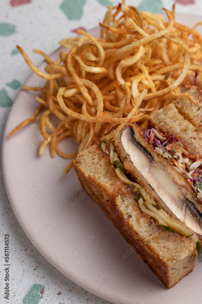Manos sosteniendo un sándwich de potobelo y coleslaw con papas fritas ...