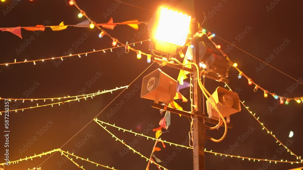 Loudspeakers hang on a pole with carnival ribbons in the night sky ...