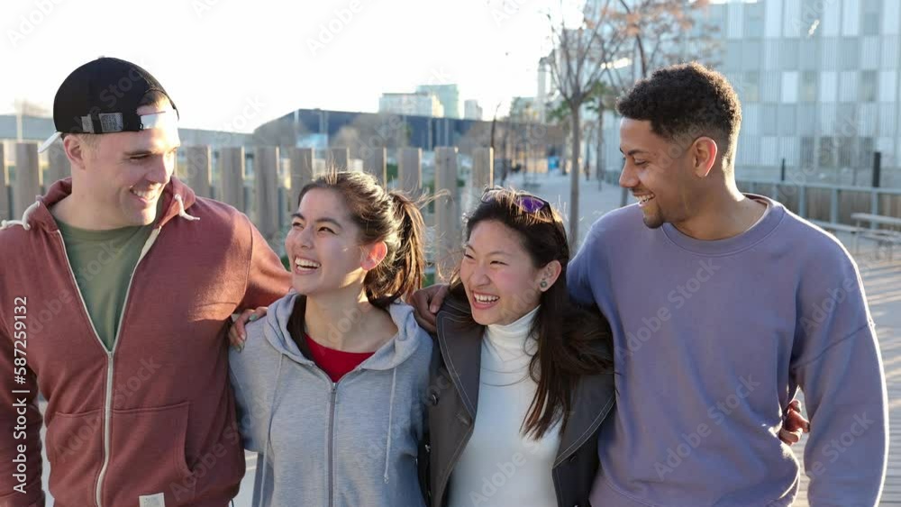 Happy diverse young friends walking together hugging each other ...