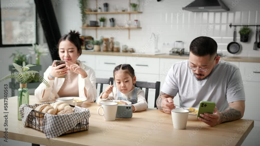 Family Eating And Watching Smartphones Ignoring Each Other. Asian ...