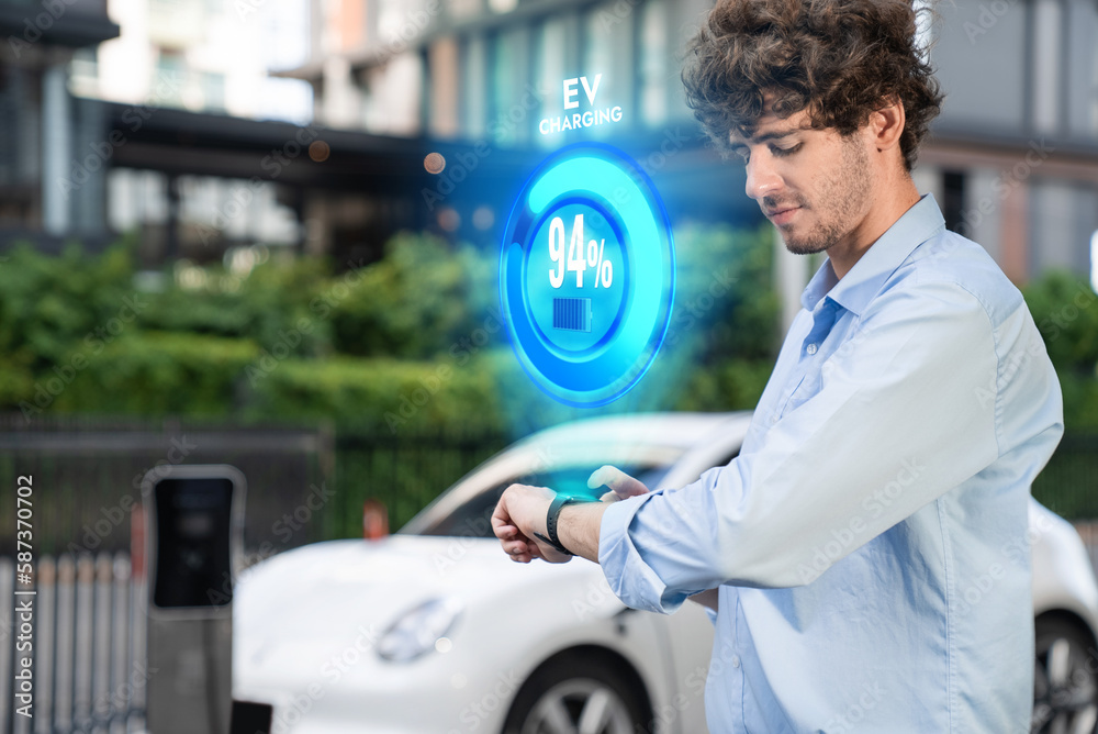 Progressive businessman check wearable hologram watch on electric car ...