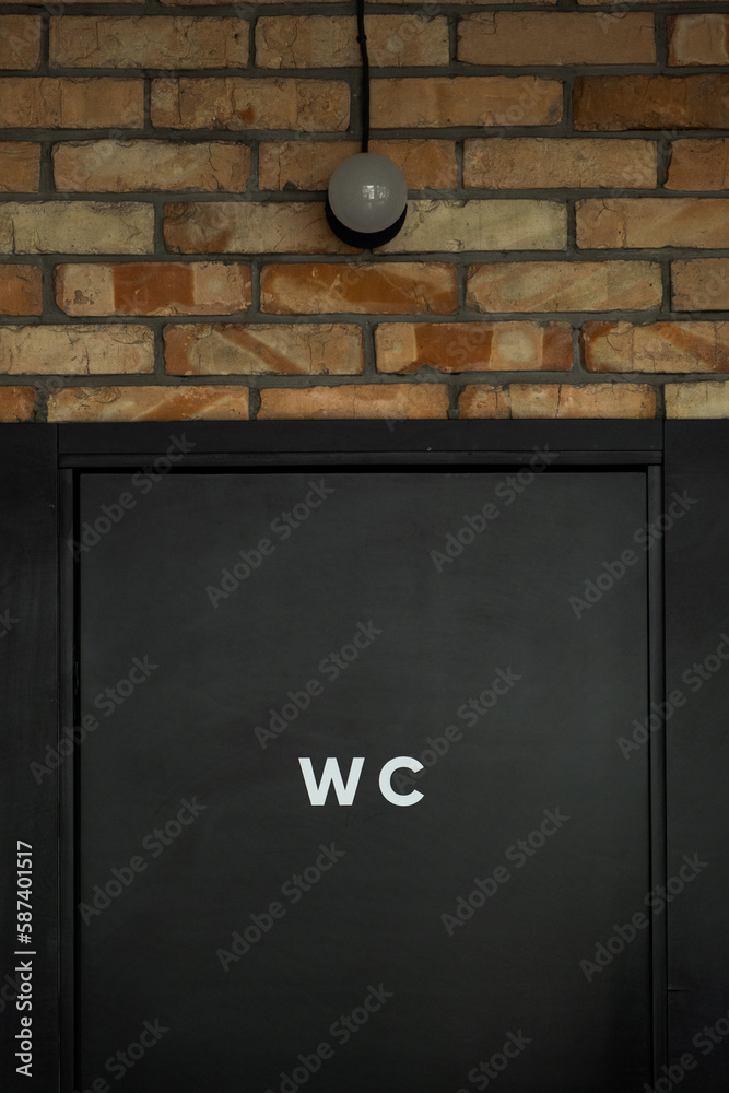 Black restroom door with a WC sign on it. Modern public toilet entrance ...