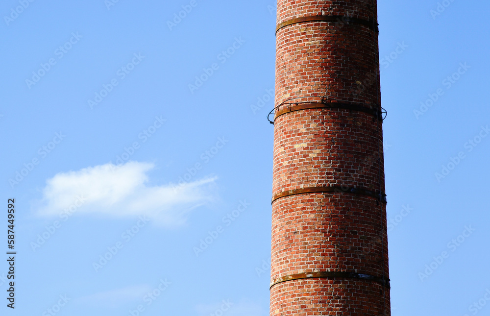 tall tapered large brick chimney stack closeup. rusty metal reinforcing ...