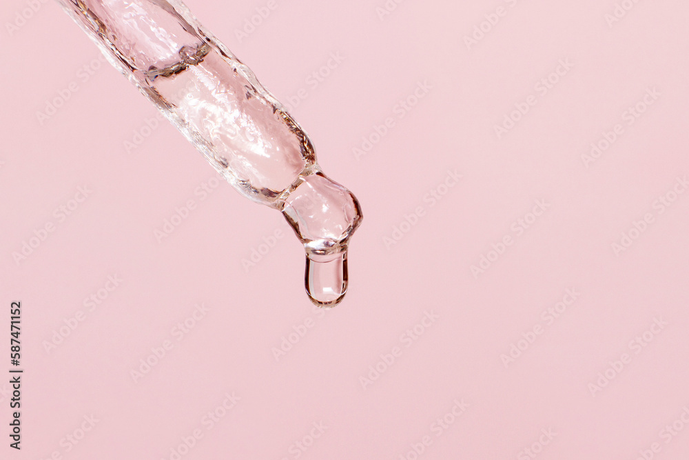 Cosmetic pipette with dripping liquid and drops on a pink background ...