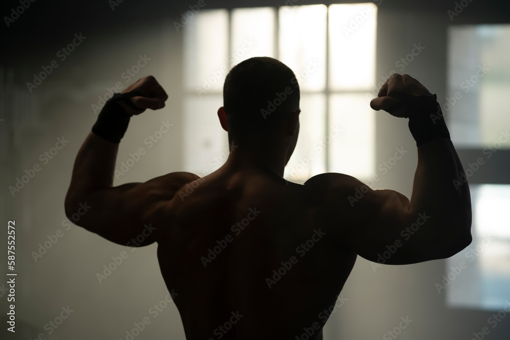 Strong muscular man flexing muscles from the back. He is showing back ...