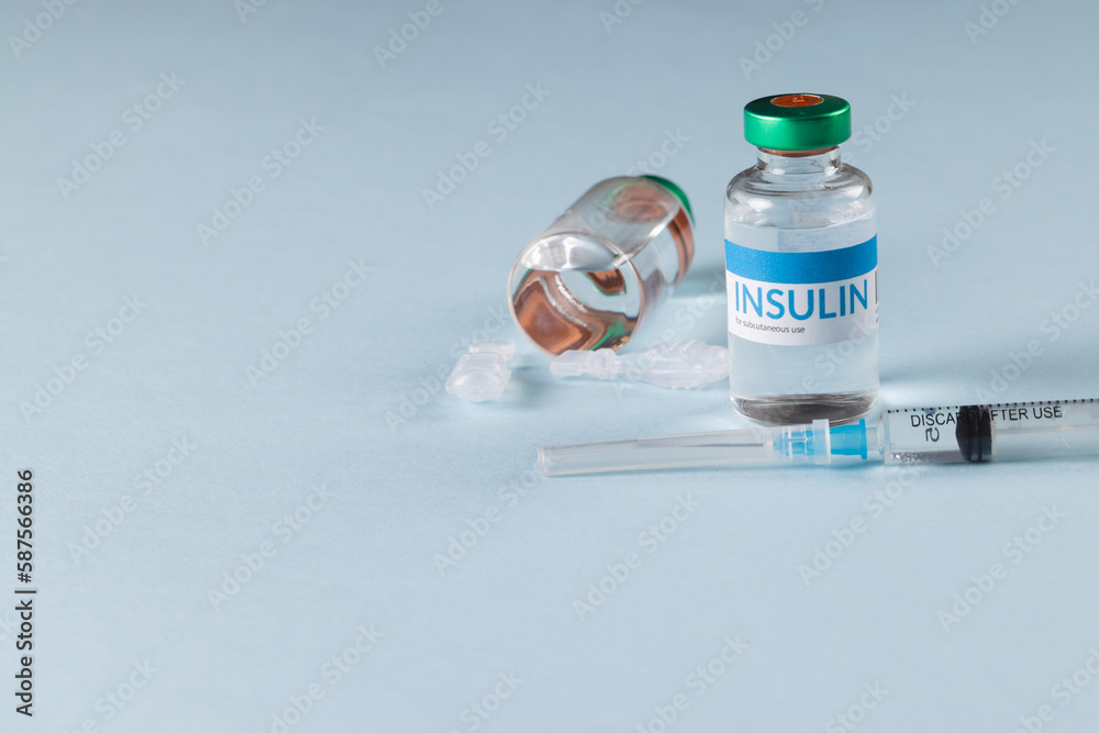 Vials of insulin with caplets and syringe on blue background with copy ...