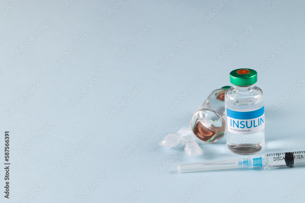 Vials of insulin with caplets and syringe on blue background with copy ...