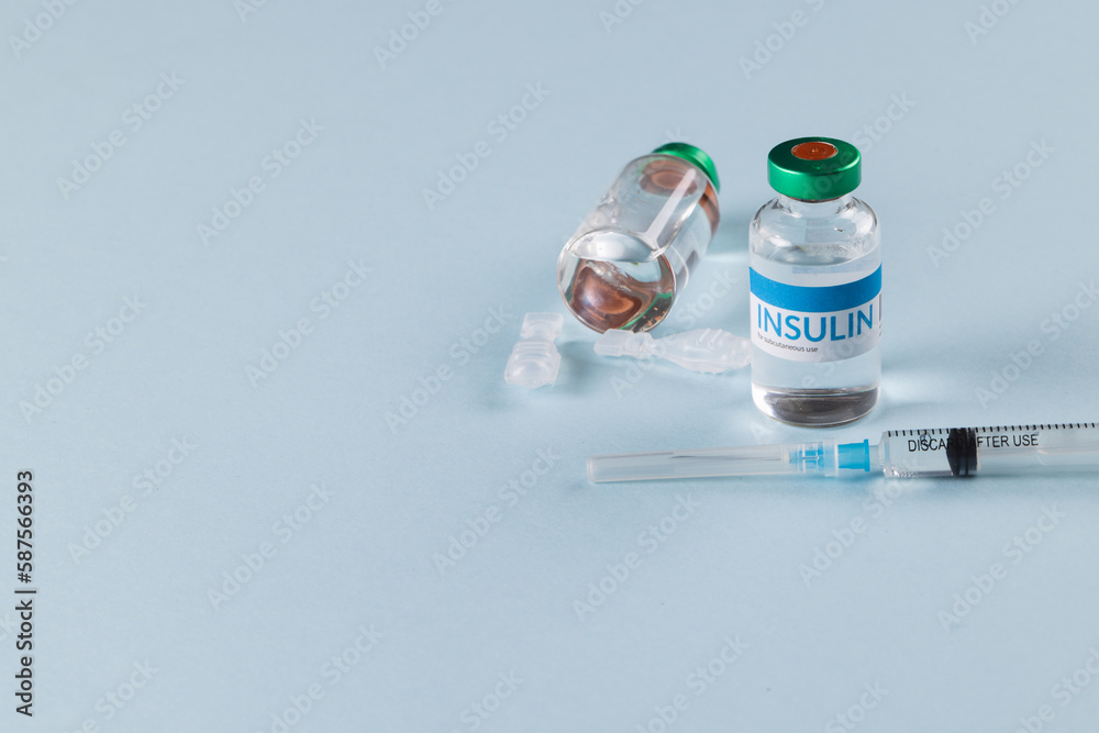 Vials of insulin with caplets and syringe on blue background with copy ...
