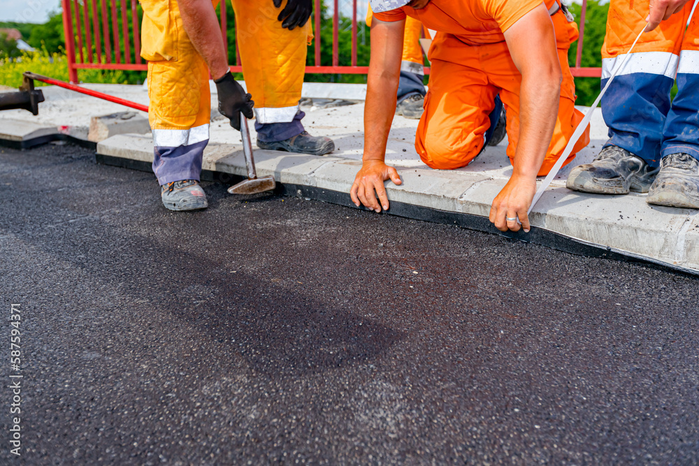 Workers apply black bitumen membrane strips for waterproofing roads and ...