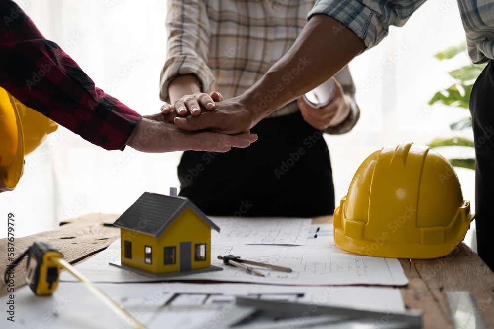 Architect and engineer construction workers stacking hands while ...