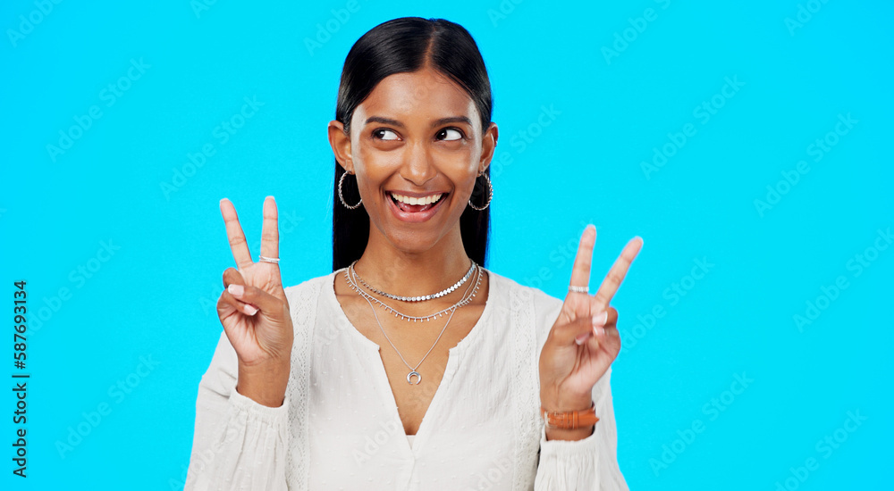Happy woman, peace and face wink in studio, blue background and color ...