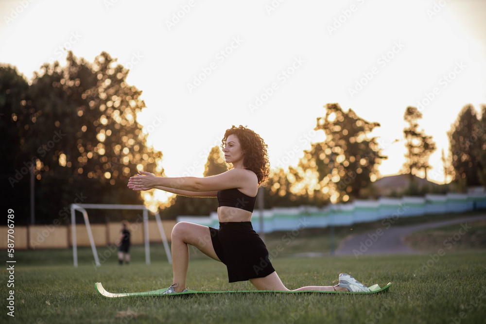 young woman mother goes in for sports gymnastics in summer on a ...