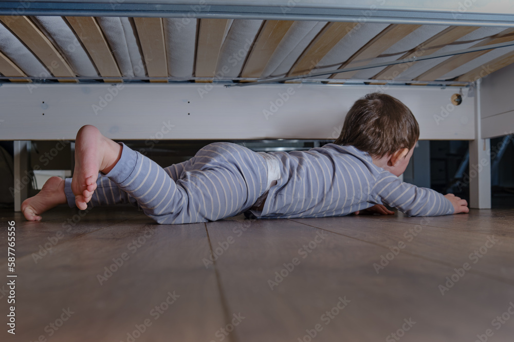 Toddler baby crawls and hides under the bed. Child climbed under the ...