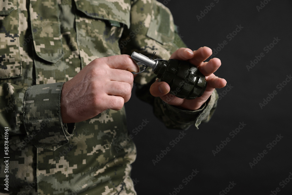 Soldier pulling safety pin out of hand grenade on black background ...