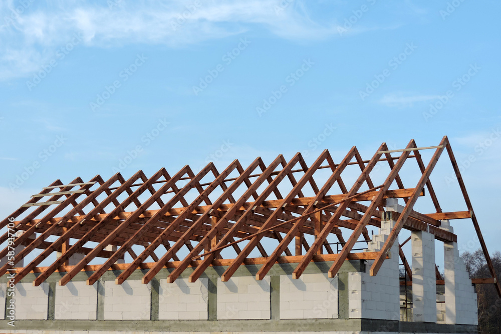 A timber roof truss in a house under construction, walls made of concrete blocks, rough window ...
