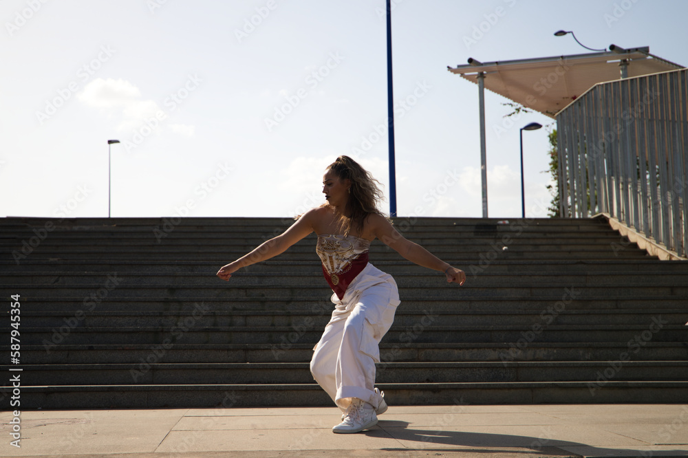 Latin woman, young and beautiful dancing modern dance in the street and ...