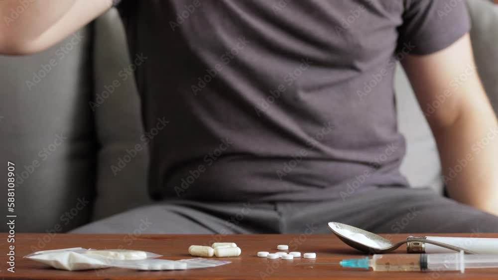 Addicted man sitting on a sofa, drinking alcohol from a glass and ...