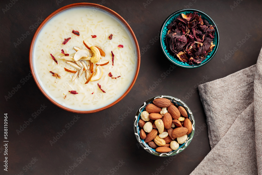 Rice kheer, nuts and dried hibiscus flowers on a dark background ...
