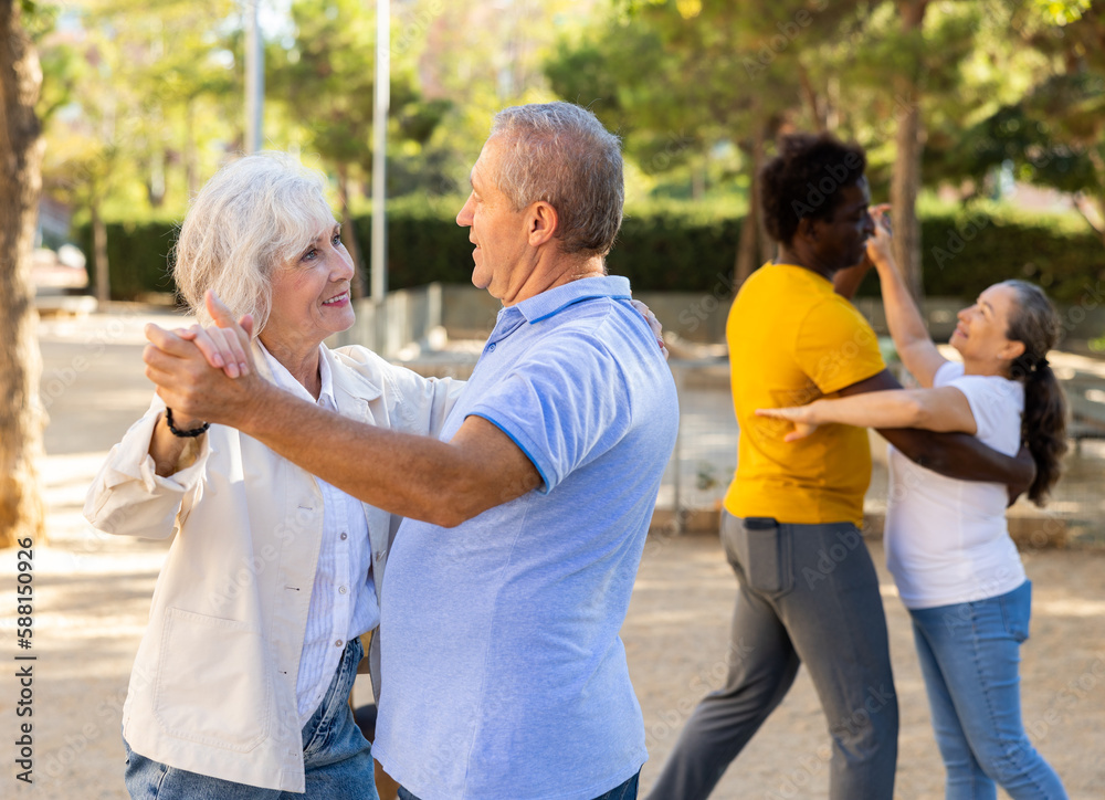 Two couples of mixed-race men and women of different age dancing ...