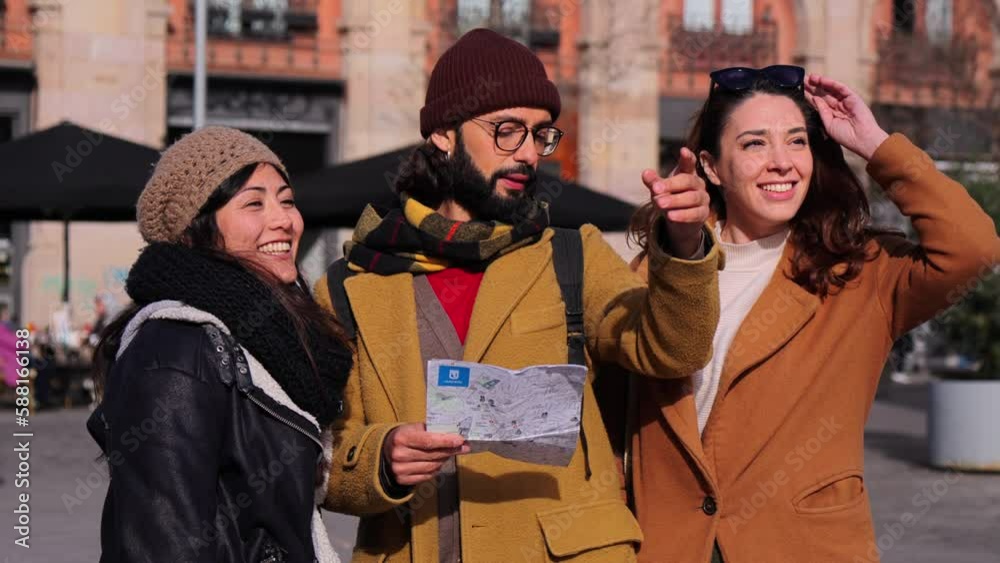 three tourist happy friends looking for directions on a map enjoying ...
